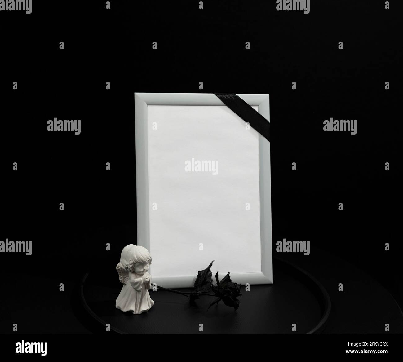 White frame with black mourning ribbon, black rose and an angel ...