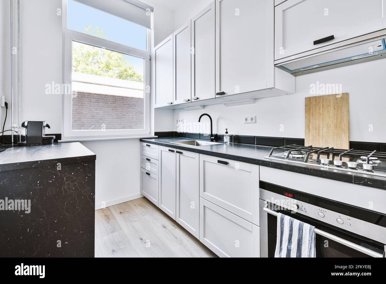 Kitchen with white cabinets near window in flat Stock Photo - Alamy
