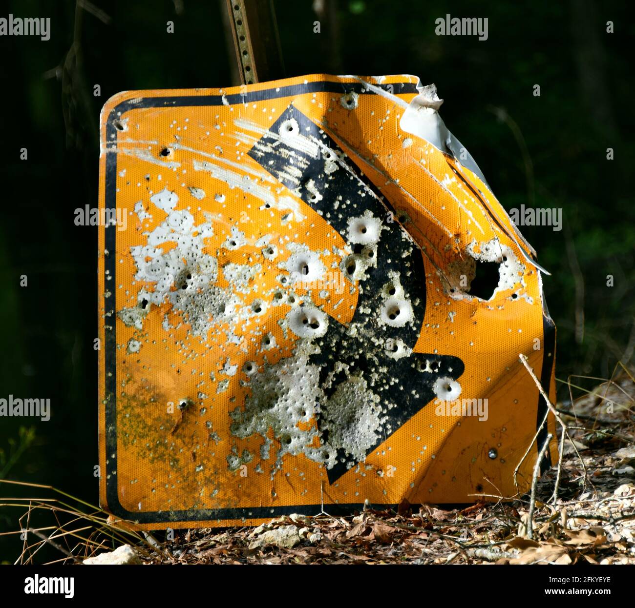 Curve sign has been torn down and bullet holes riddle its surface. Sign ...