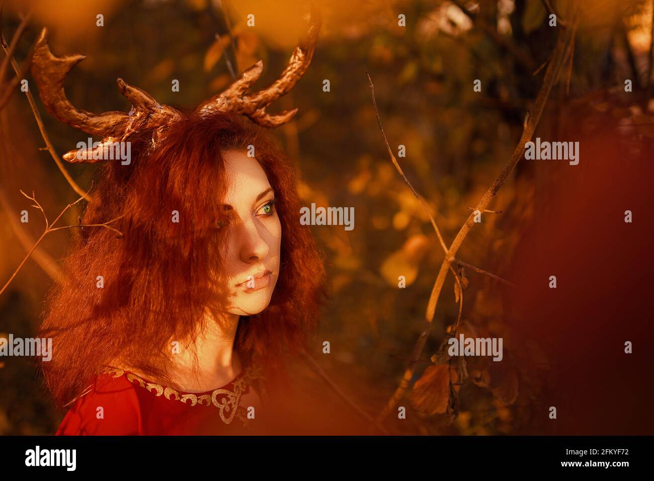 Woman in long red dress with deer horns in autumn forest. Beautiful ...