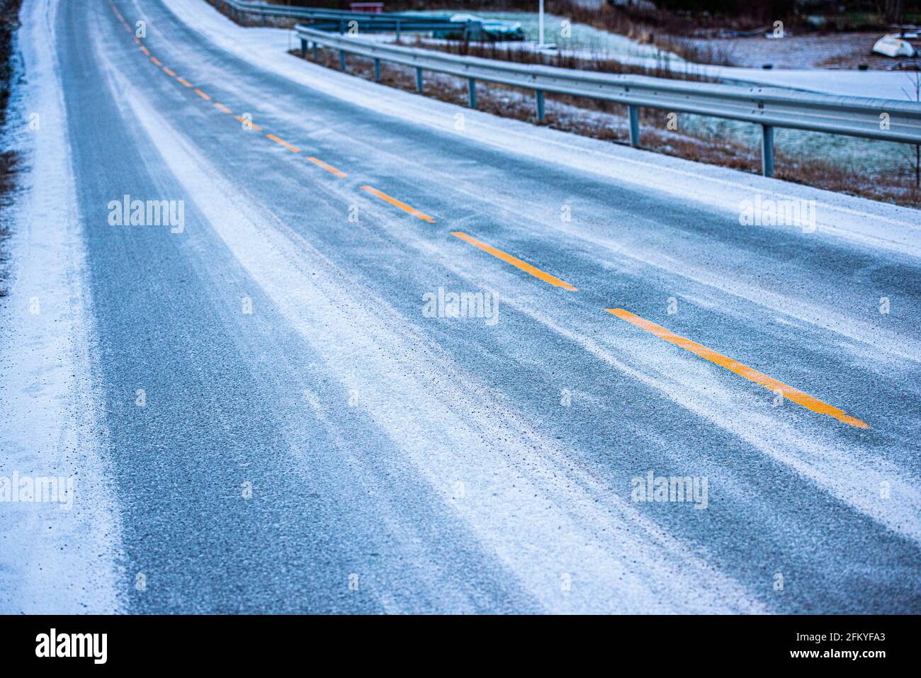 Ice covered road with tire tracks and yellow road markings Stock Photo ...