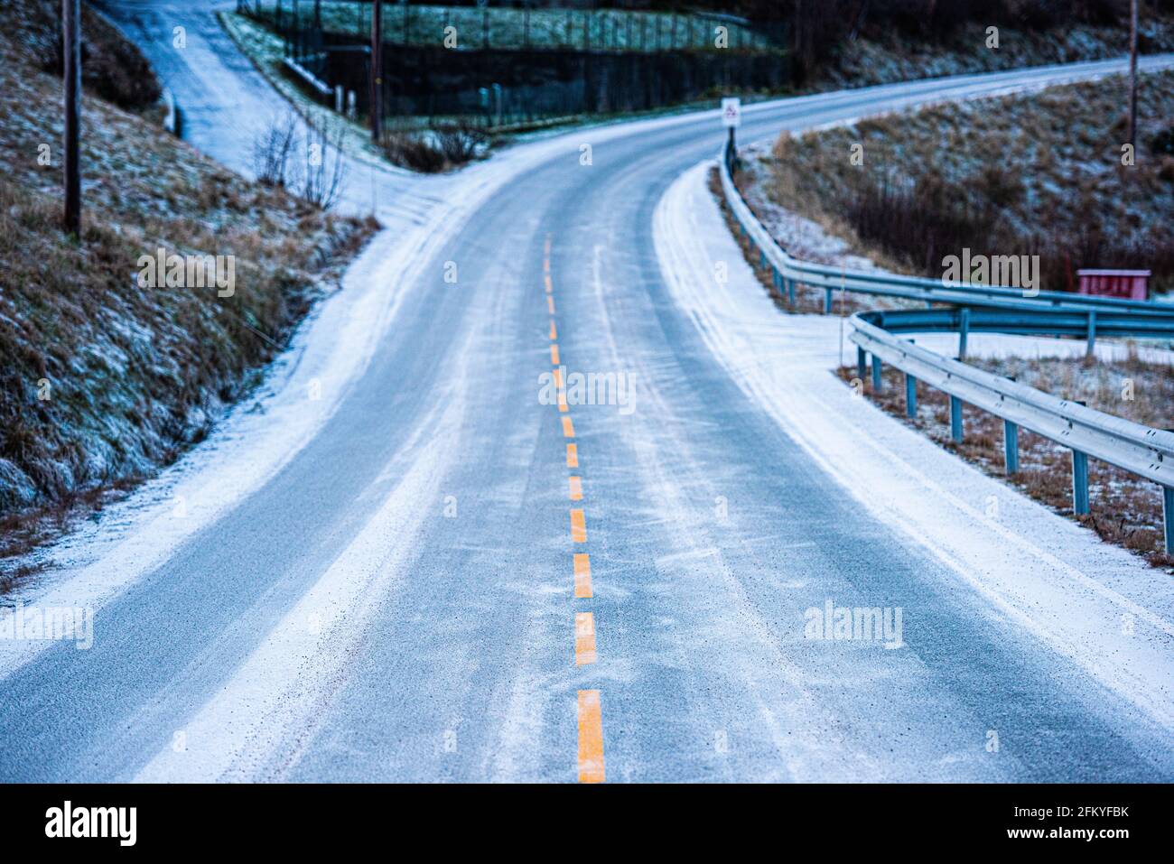 Ice covered road with tire tracks and yellow road markings Stock Photo ...