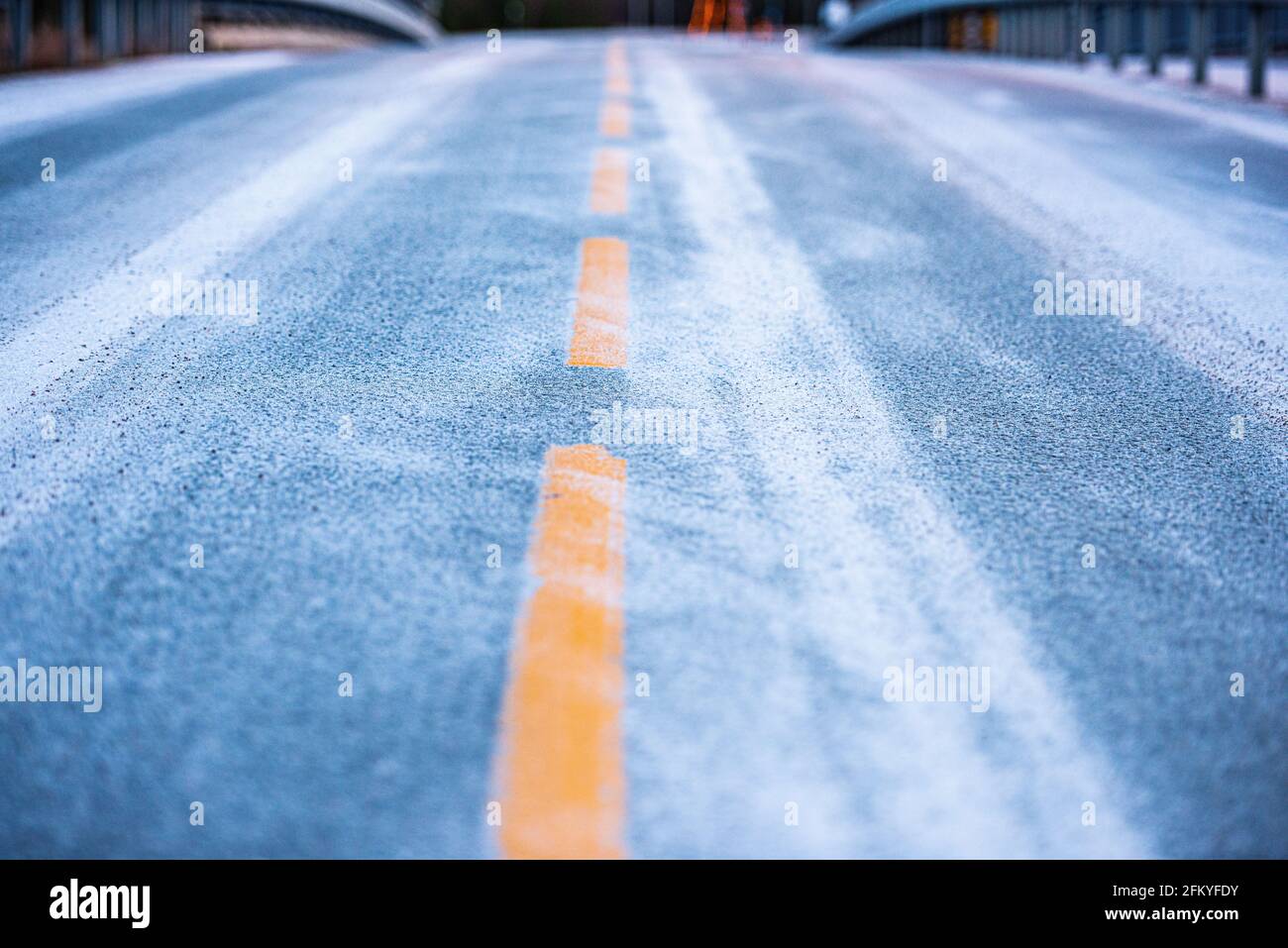 Ice covered road with tire tracks and yellow road markings Stock Photo ...