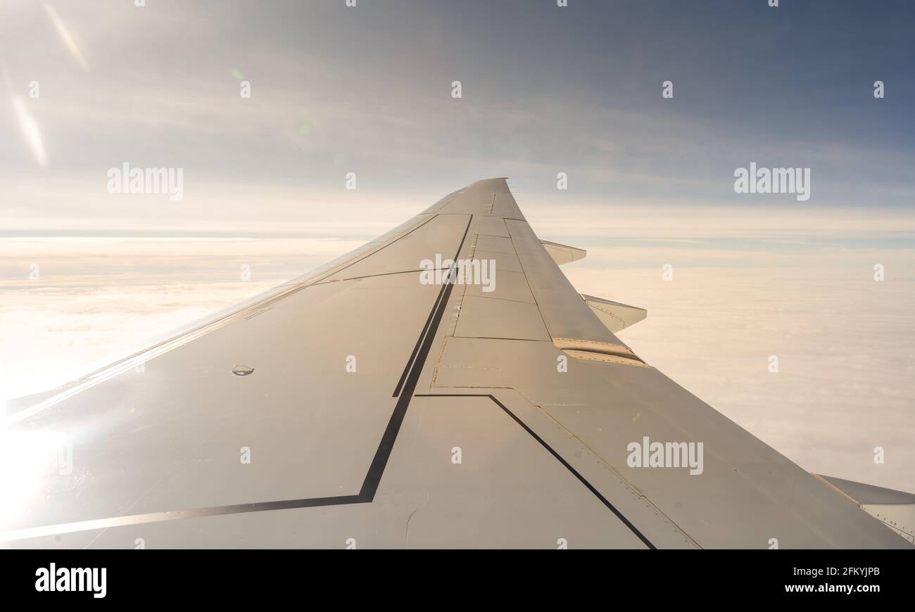 Wing of an airplane in foreground flying above sea of clouds. Travel ...