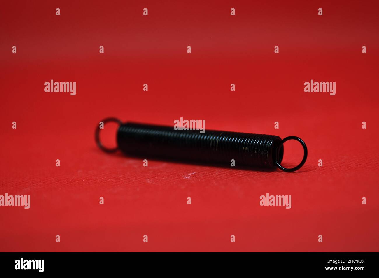 Closeup of a black metal spring isolated on a red background Stock ...