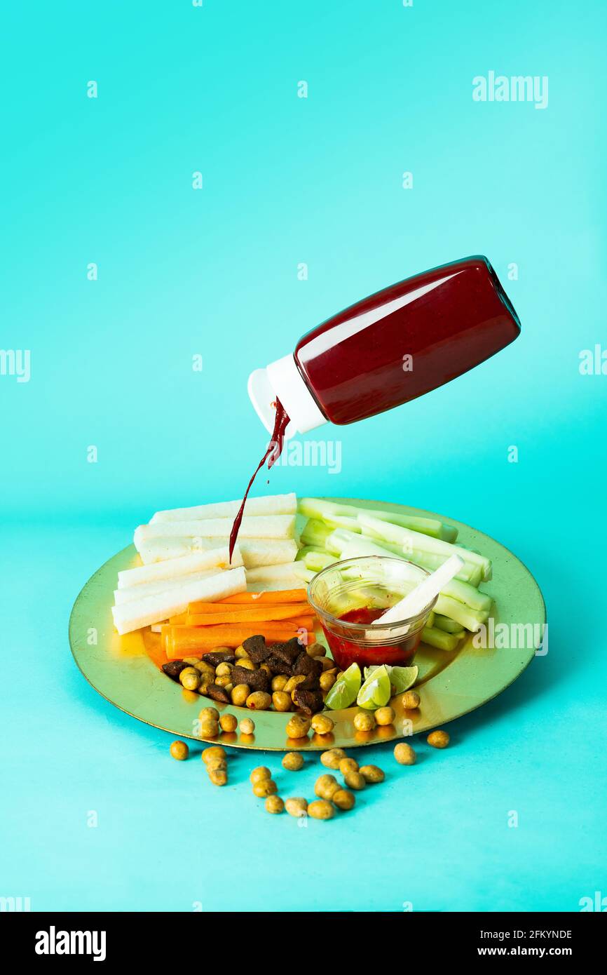 A vertical shot of pouring ketchup on sliced turnip, cucumber, carrots ...