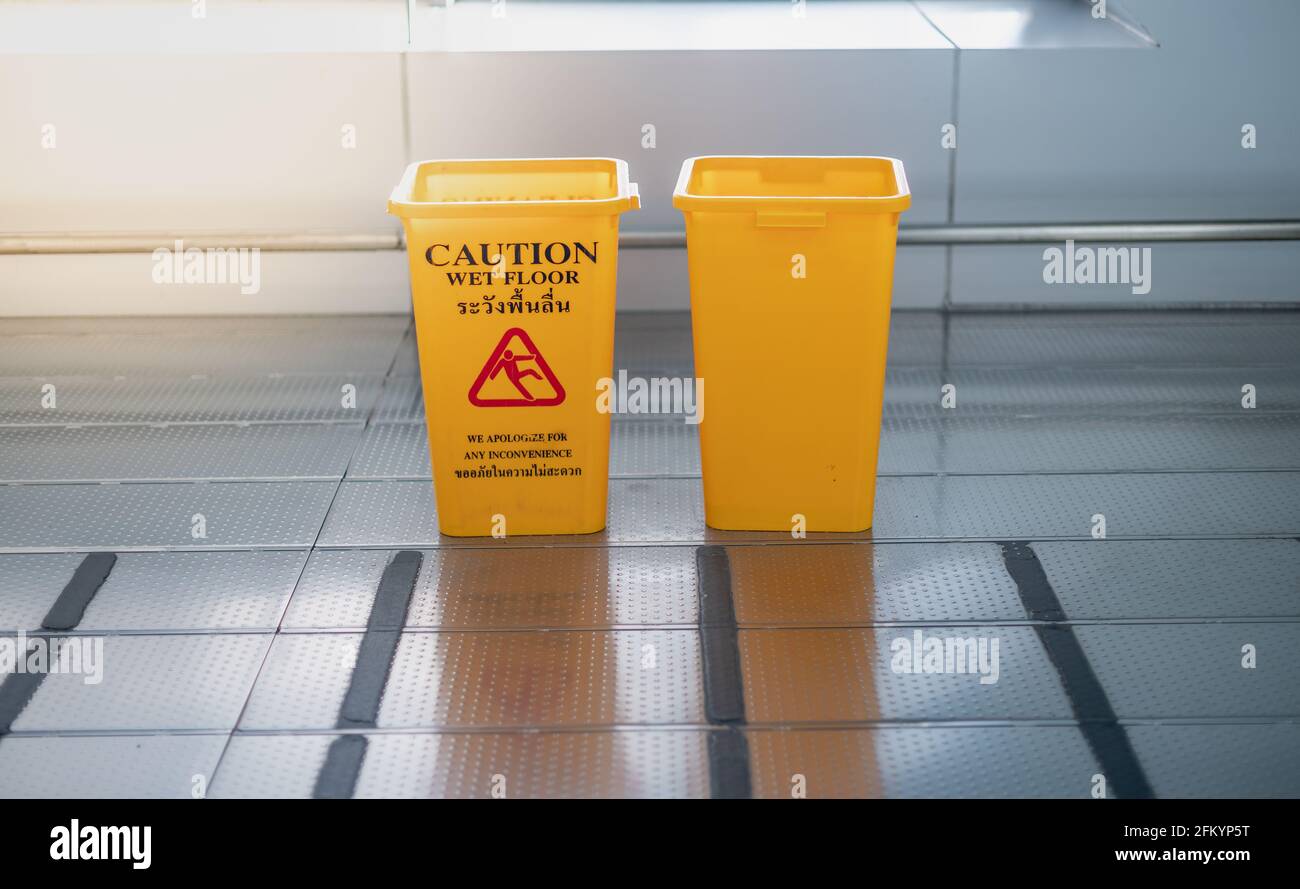 The yellow garbage bin and caution wet floor sign for the people . The ...