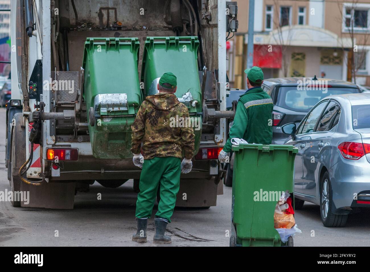 Garbage truck and workers collecting solid waste in residential area ...