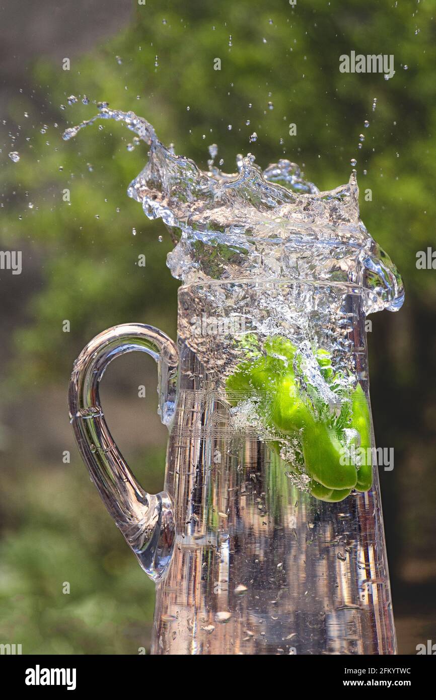 Green pepper being submerged into a glass jug outside while causing big ...