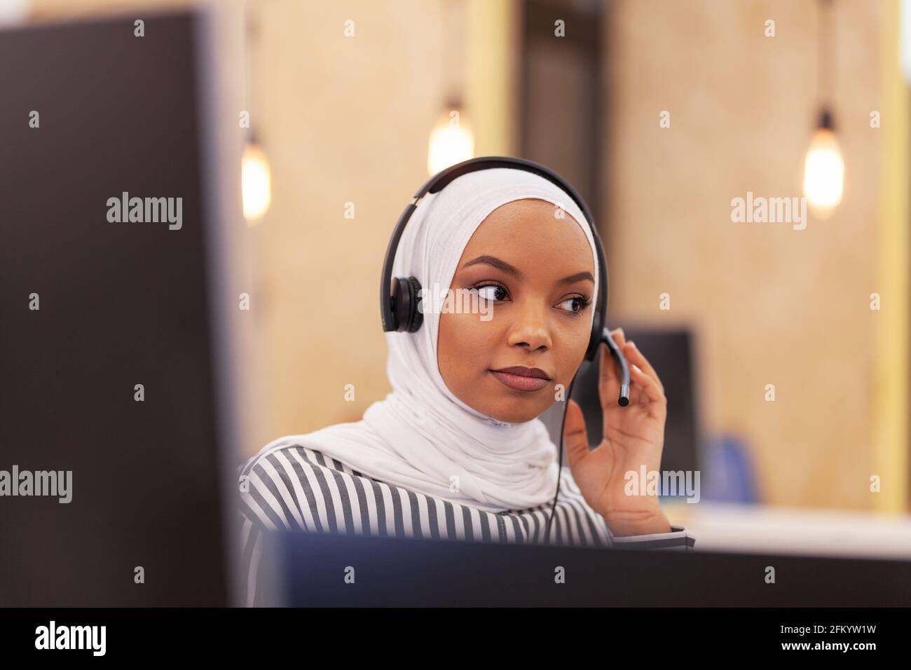African american muslim girl with hijab and headset in a modern office ...