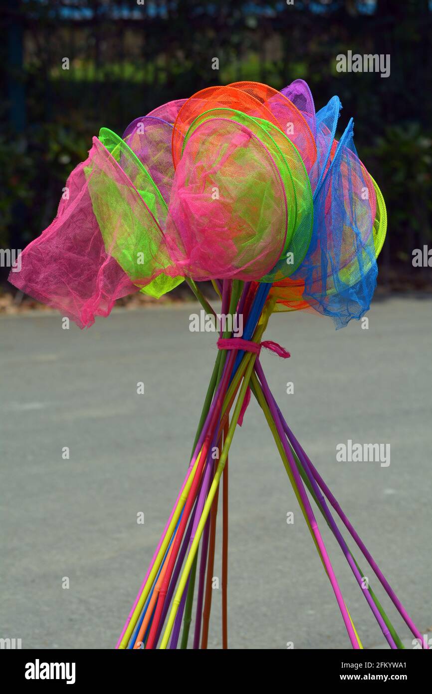 Stack of different colour childrens fishing nets, bamboo sticks and ...
