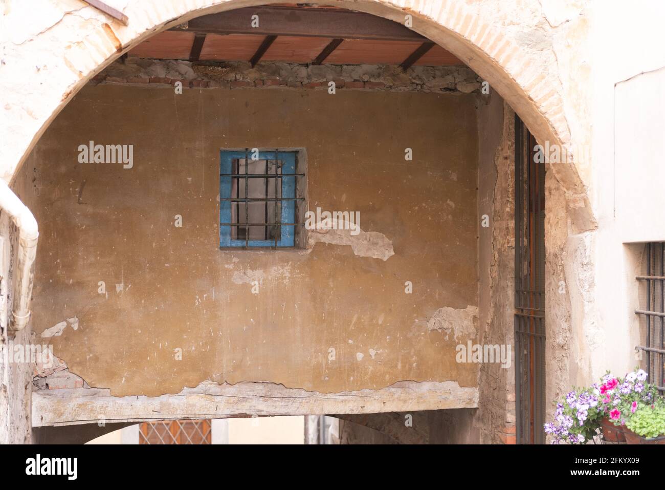 Barred window under the arch. An arch under one of the houses in Barga ...