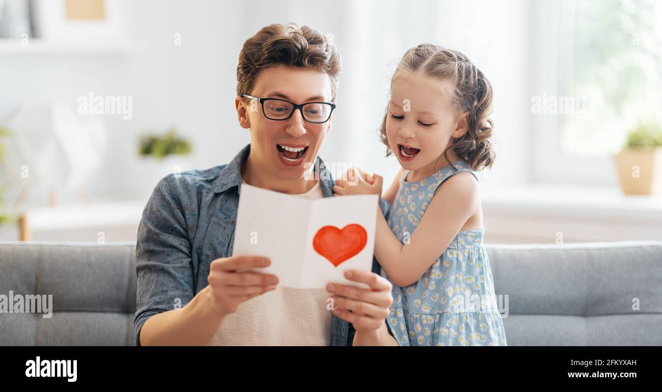 Child daughter is congratulating her father and giving him postcard ...