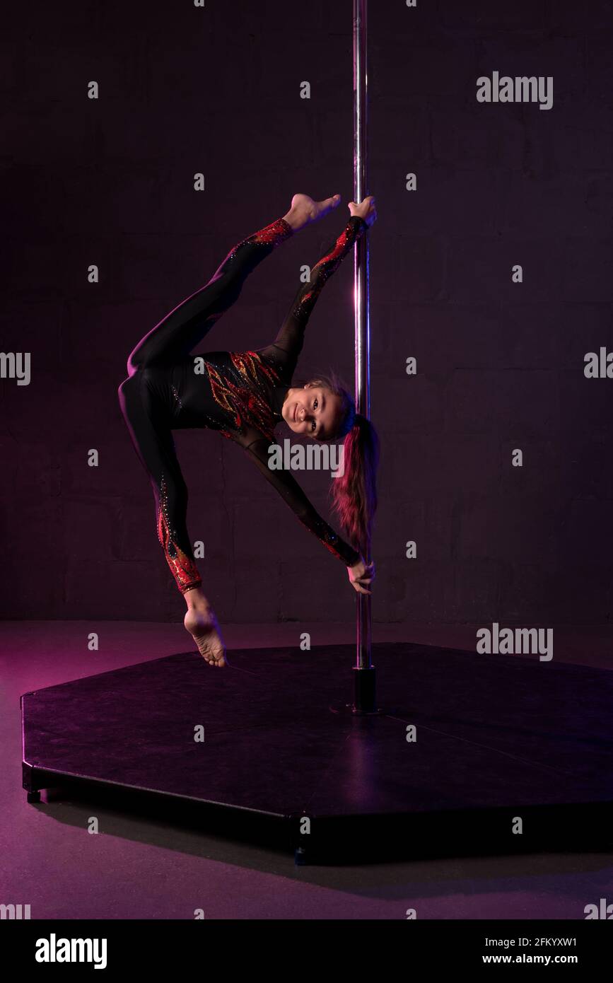 Graceful teem girl doing gymnastic split on pole in darkness Stock ...