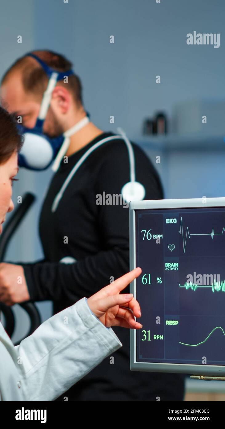 Muscular athlete with mask running on cross trainer in medical ...
