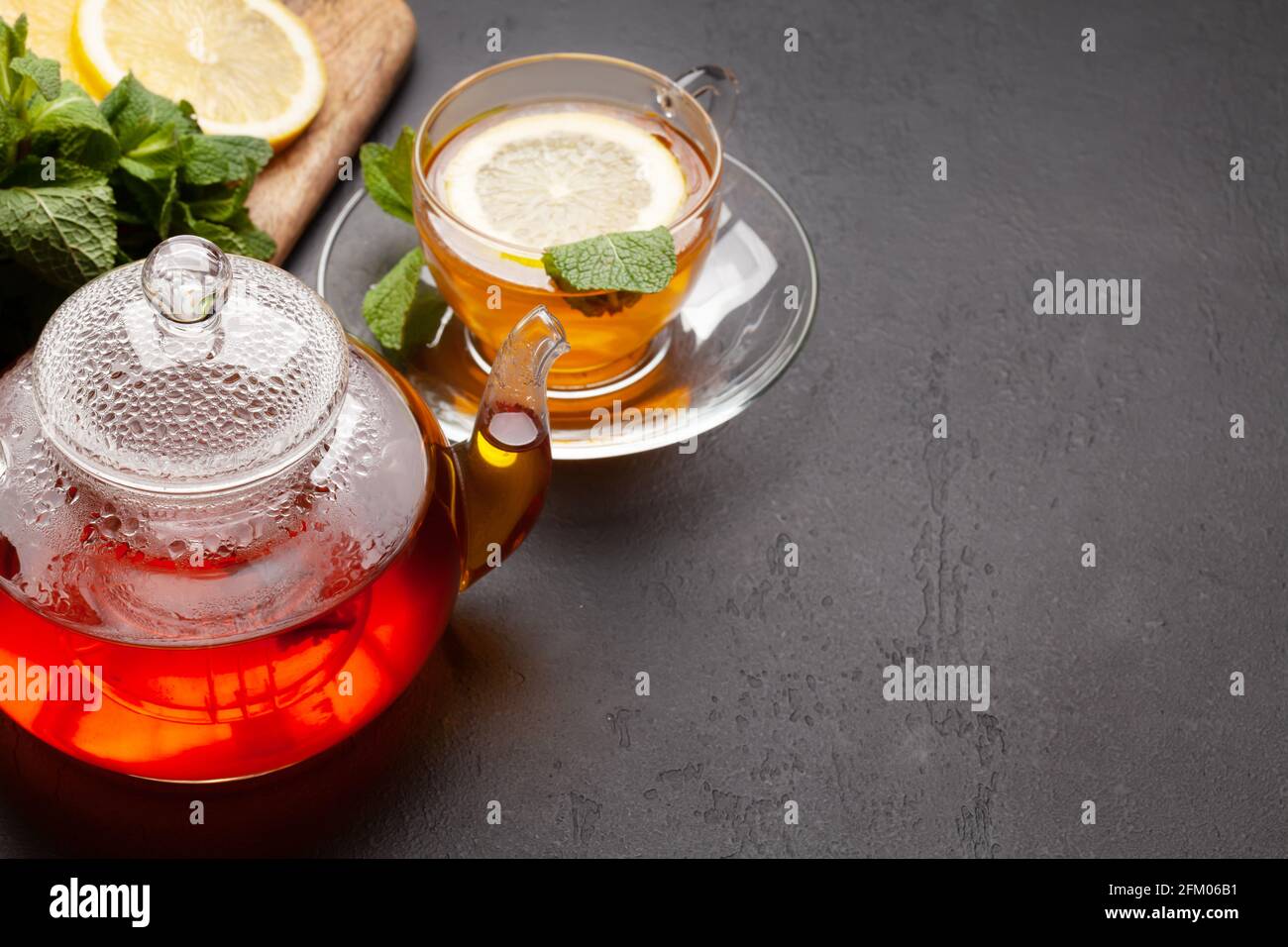 Herbal tea with mint and lemon. Tea cup and teapot on stone table. With ...