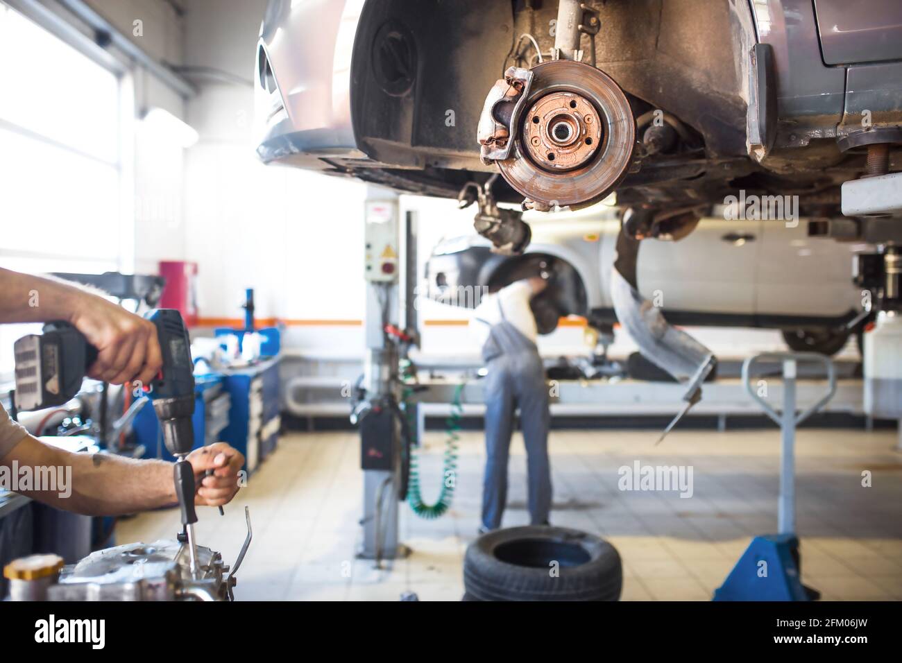 The car is lifted for repair on a lift in a car service station, a ...