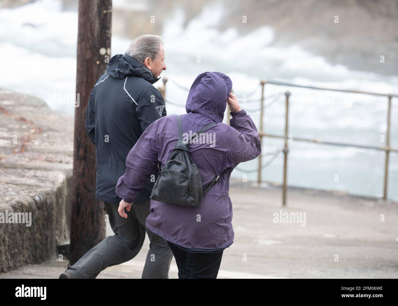 People struggle to walk against the strong winds in Porthleven ...