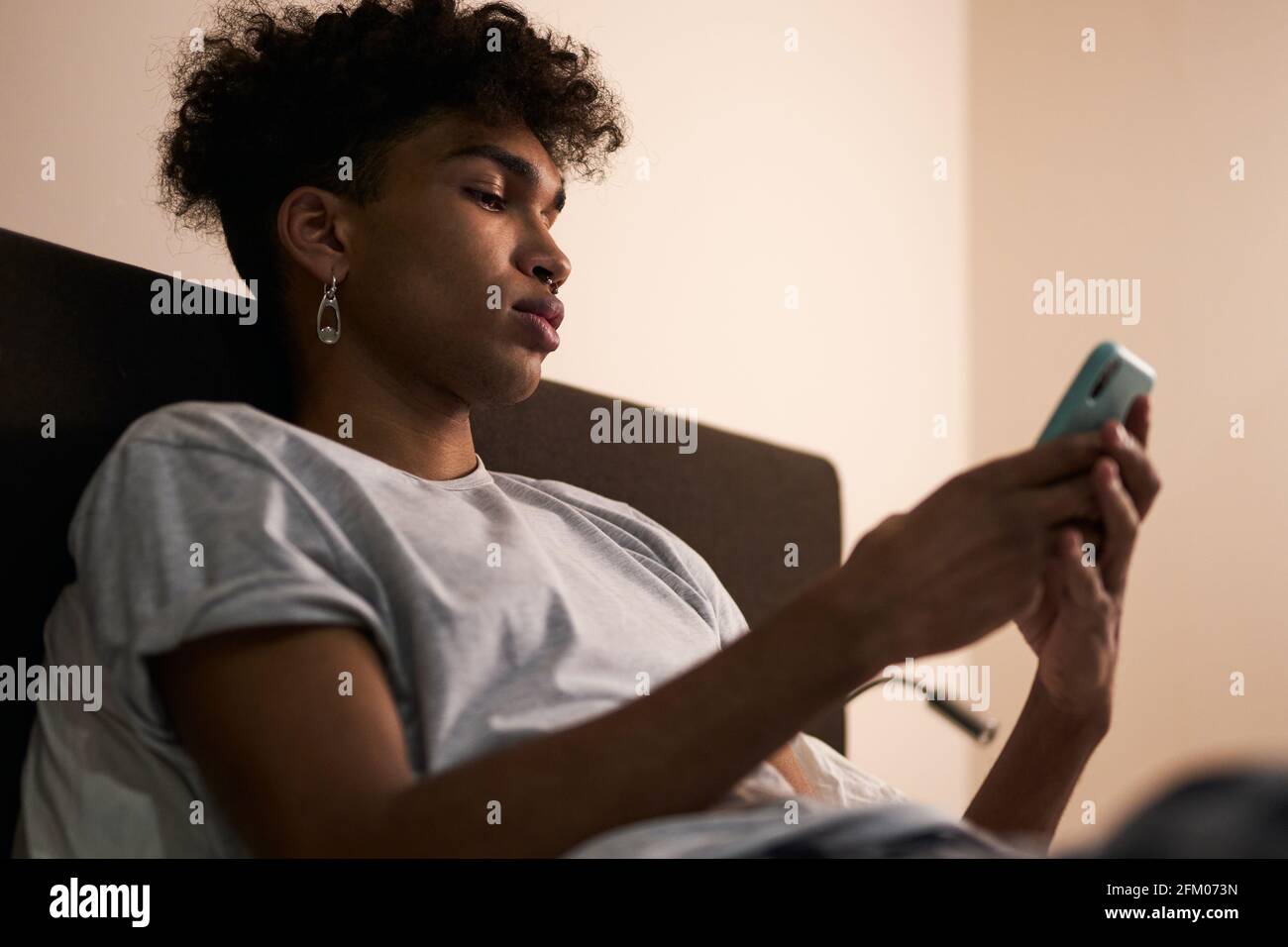 Social networks. Portrait of young guy with piercing using smartphone ...