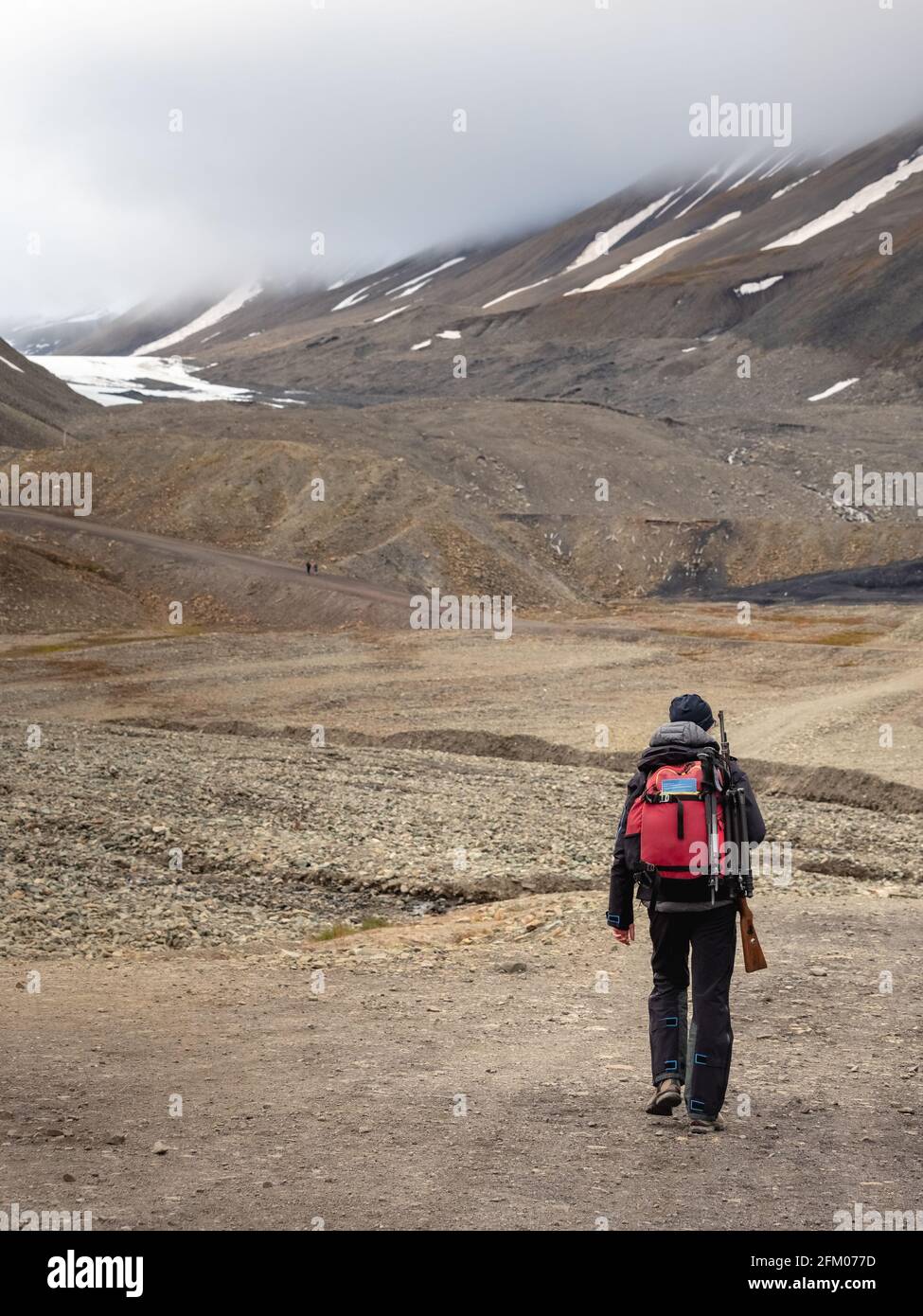 The man with a rifle hiking to the Longyear glacier. Near Longyearbyen ...