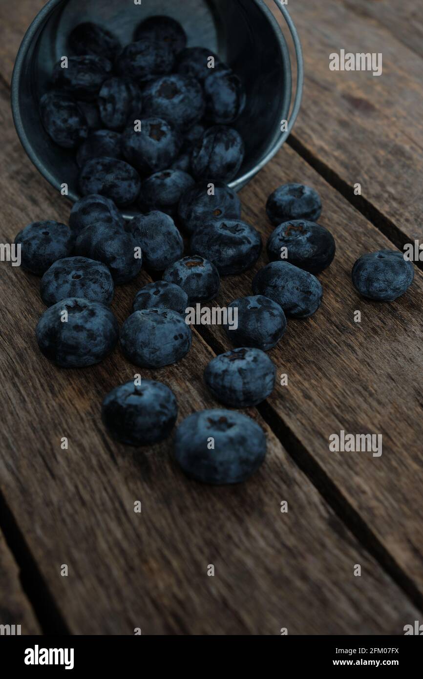 Blueberry berries spilled from metal bucket onto wooden table Stock ...