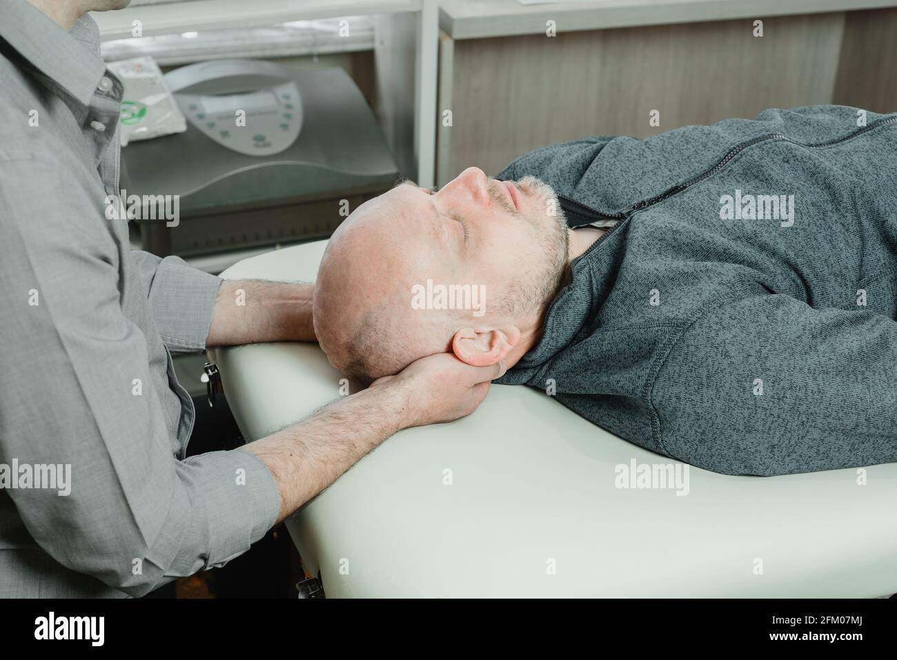 Craniosacral therapy practitioner giving a male patient CST osteopathic ...