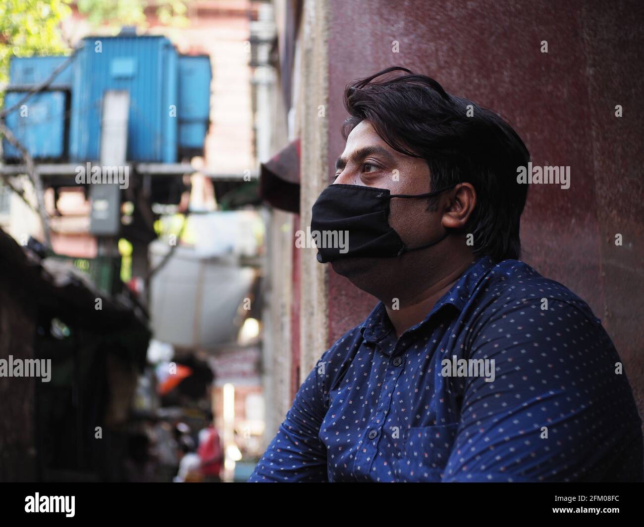 Indian man in a face mask sitting and thinking on roadside Stock Photo ...