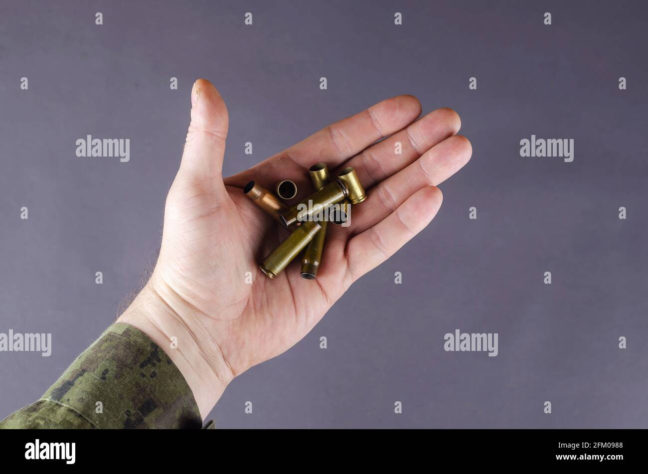 Empty casings in a man's hand against a gray background. A man in a ...