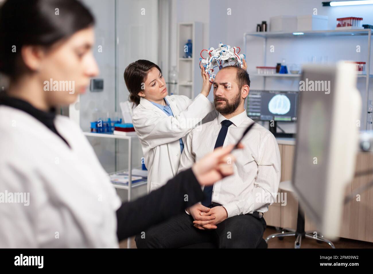 Neurology researcher adjusting brain headset on patient during study ...