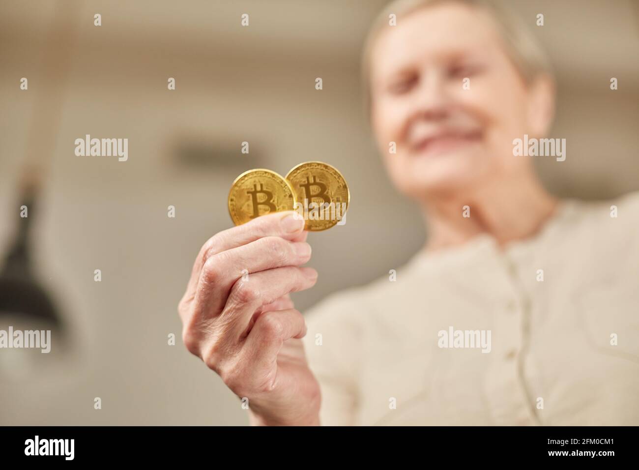 Old woman holds bitcoin coins in her hand. Senior citizen happy life ...