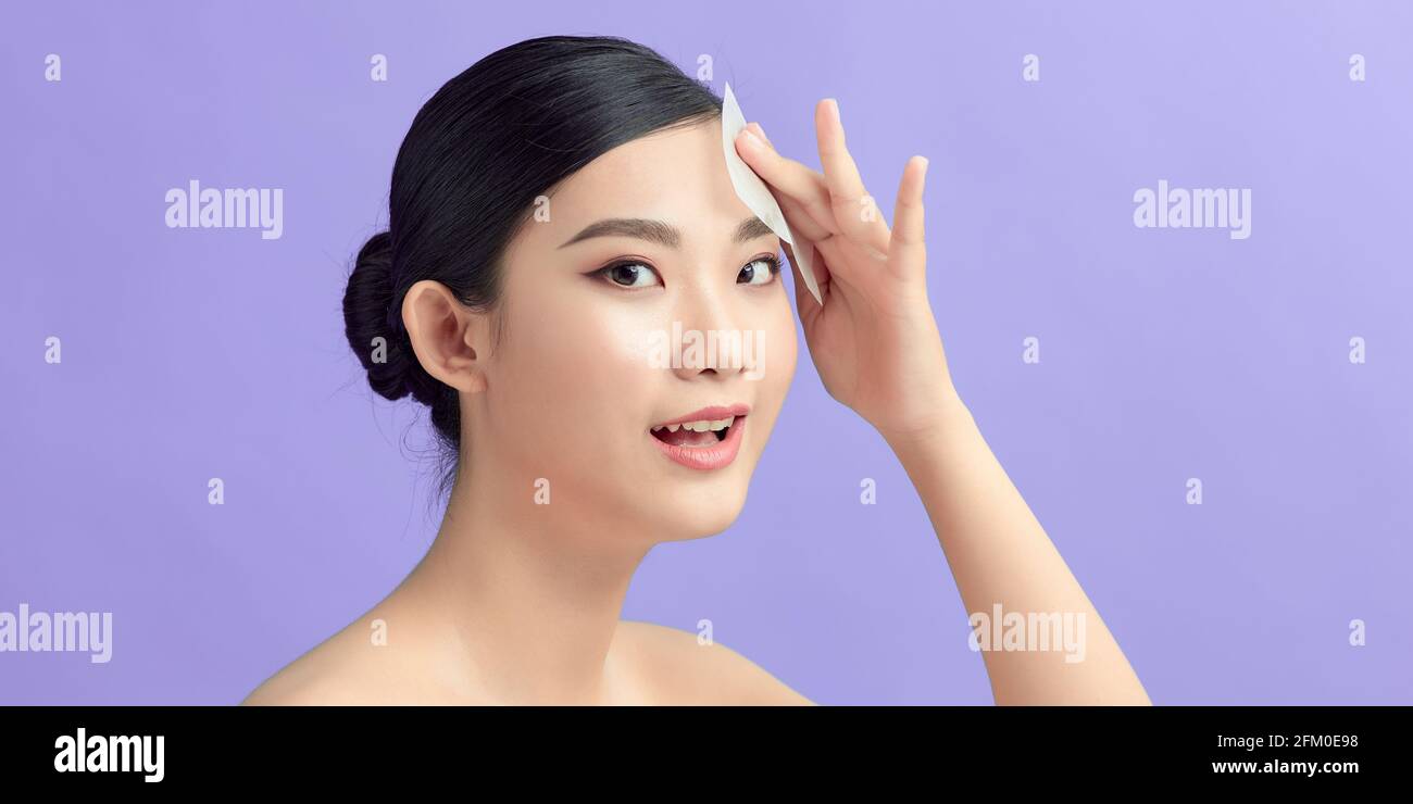 Asian woman using absorbing blotting sheets to remove excess oil on ...