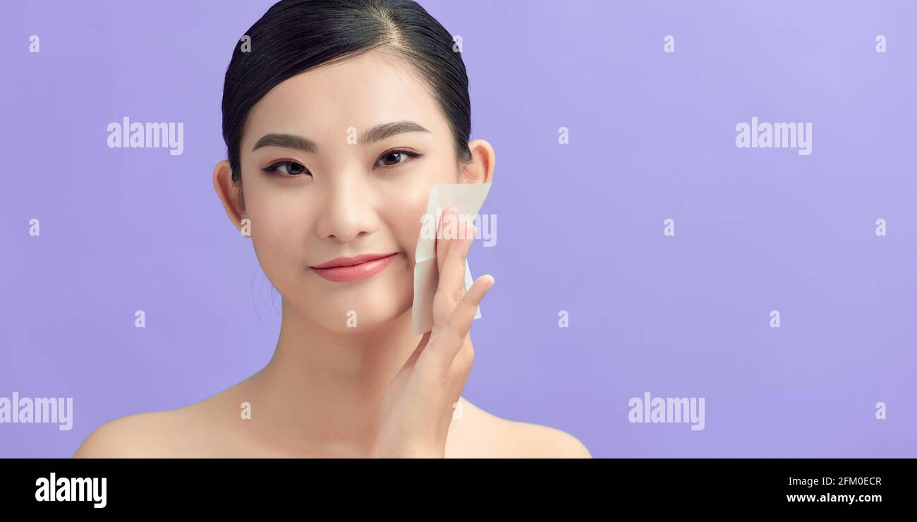 Women with oily skin using oil absorbing sheet on her face Stock Photo ...