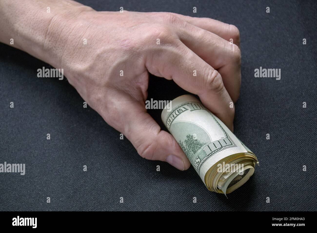 Bundle of rolled up dollar bills clutched in caucasian man's hand. Male ...