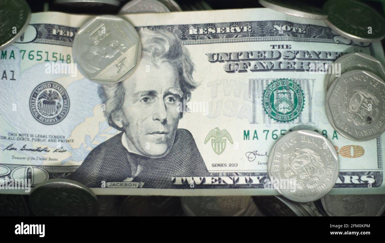 Soft focus of Peruvian sol coins and a US twenty dollar bill on white ...