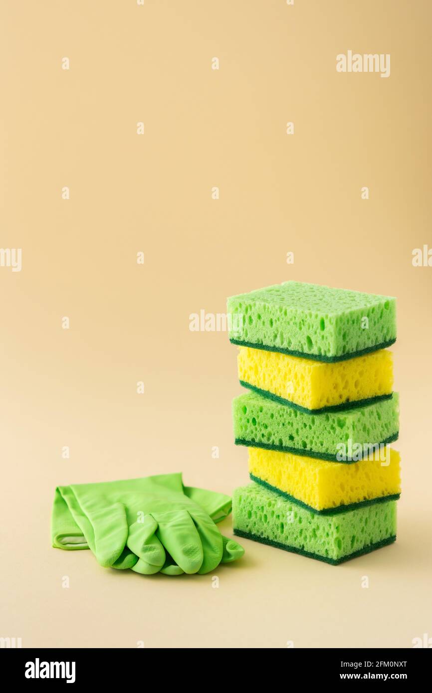 Stack of yellow and green dishwashing sponges and rubber gloves on ...