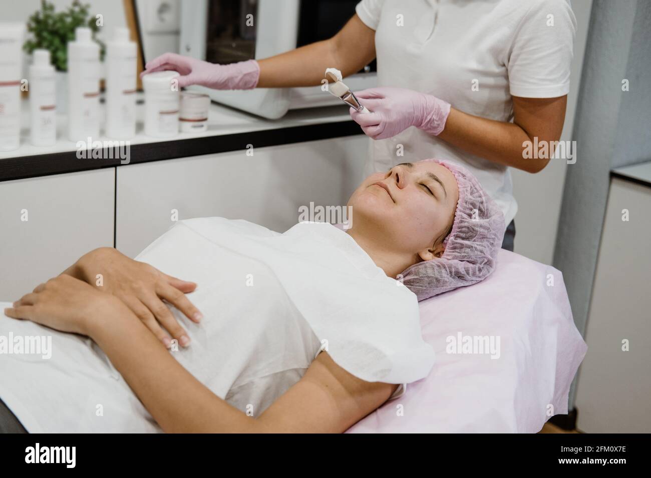 Professional Esthetician Apply Face Mask to the client's face in spa ...
