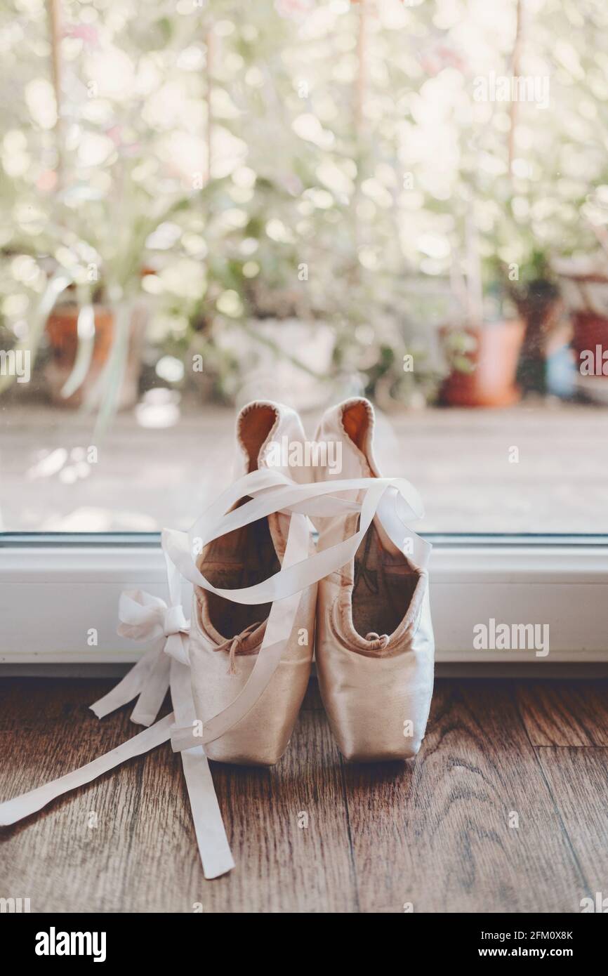 Ballet pointe shoes with pink silk ribbon near window. Old pointe shoes ...