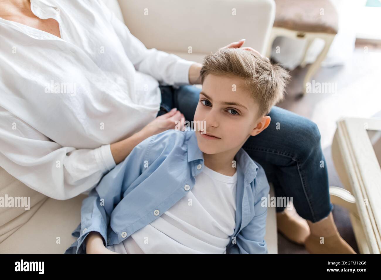 The boy lies on the lap of the woman and looks directly into the camera ...