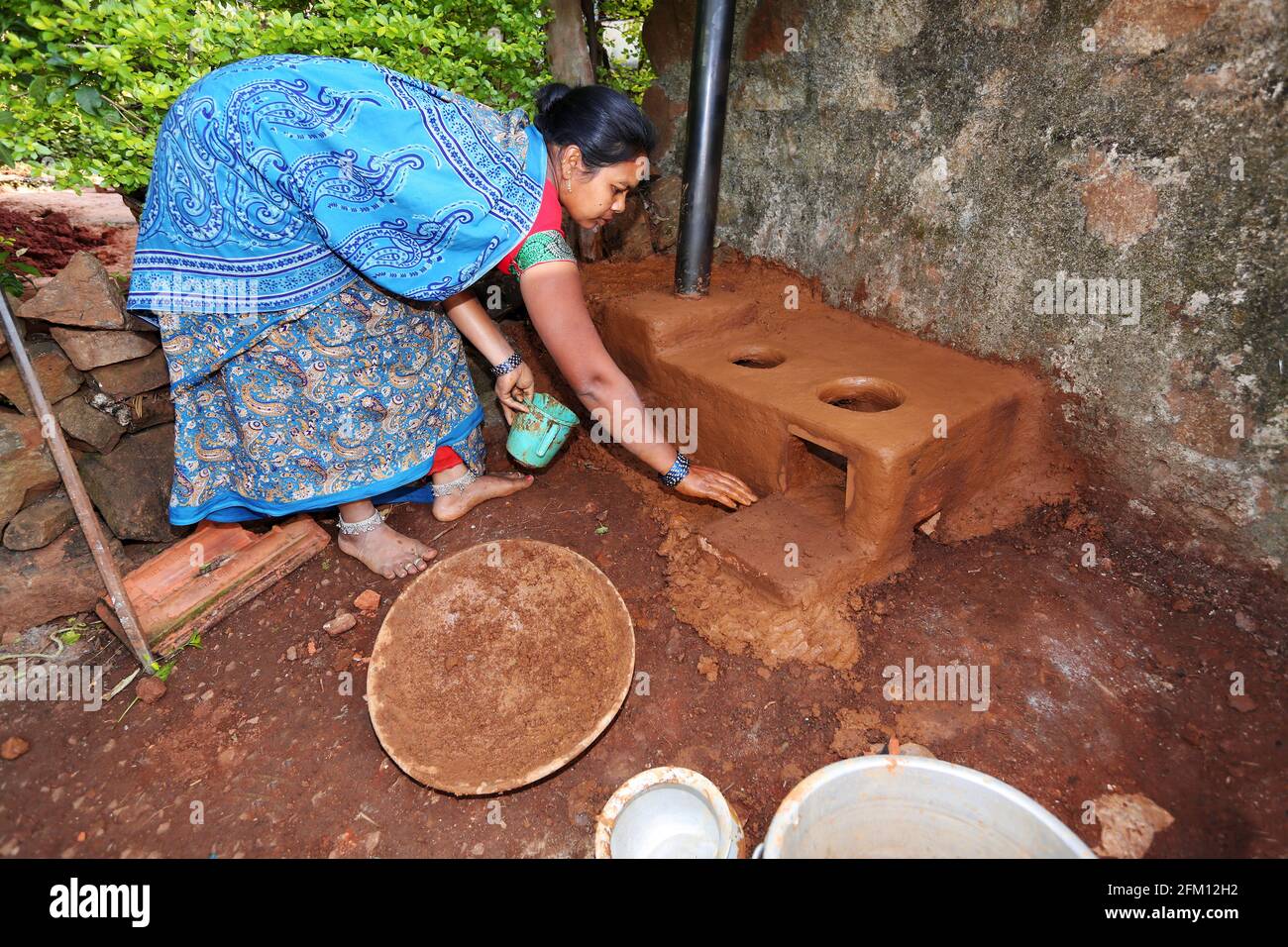 Kodhu tribal woman making traditional mud hearth at Korrakothavalasa ...