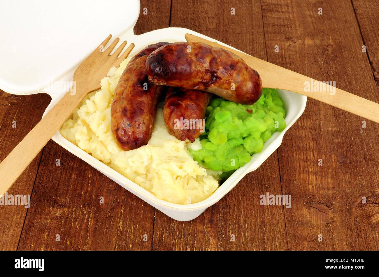 Sausages and mashed potato with mushy peas meal in a take away box on a ...