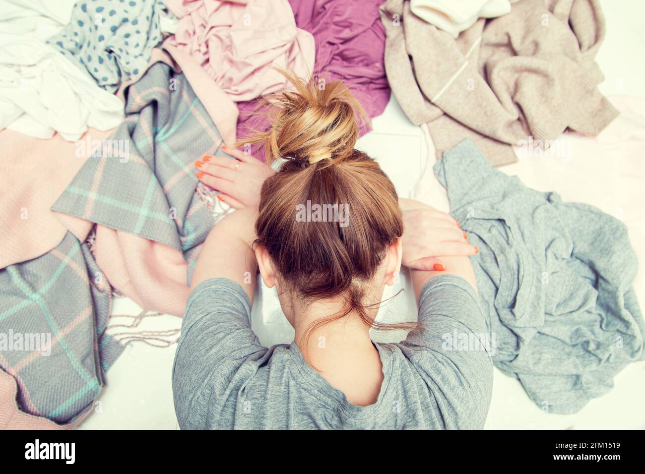 Tired housewife lies in despair on a pile of washed clothes. Household ...