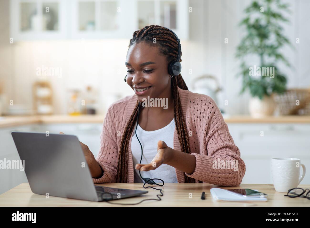Online Tutoring. Smiling black female tutor in headset using laptop in ...