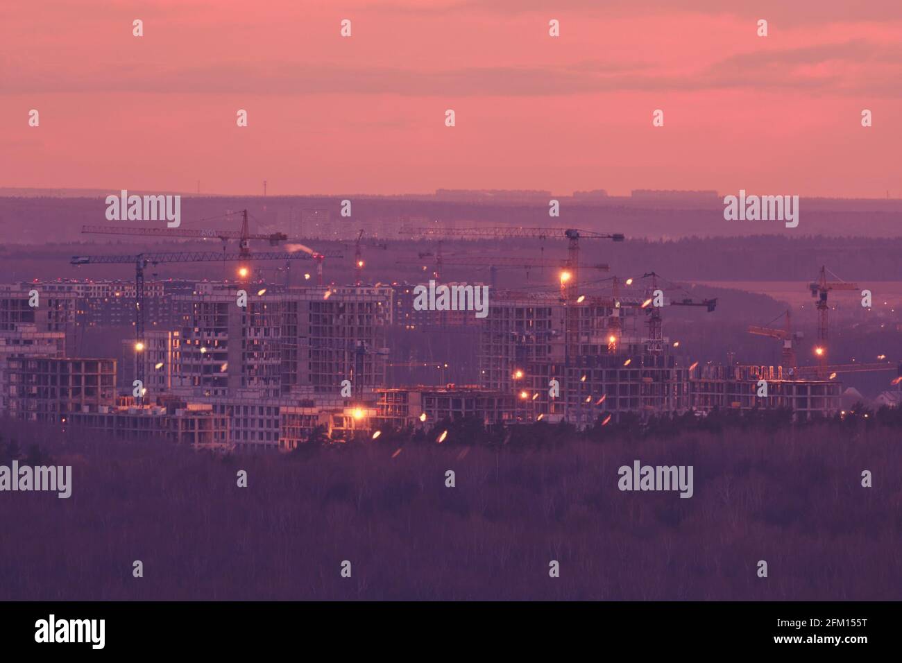 Sunset sky over under construction city buildings with tower cranes ...