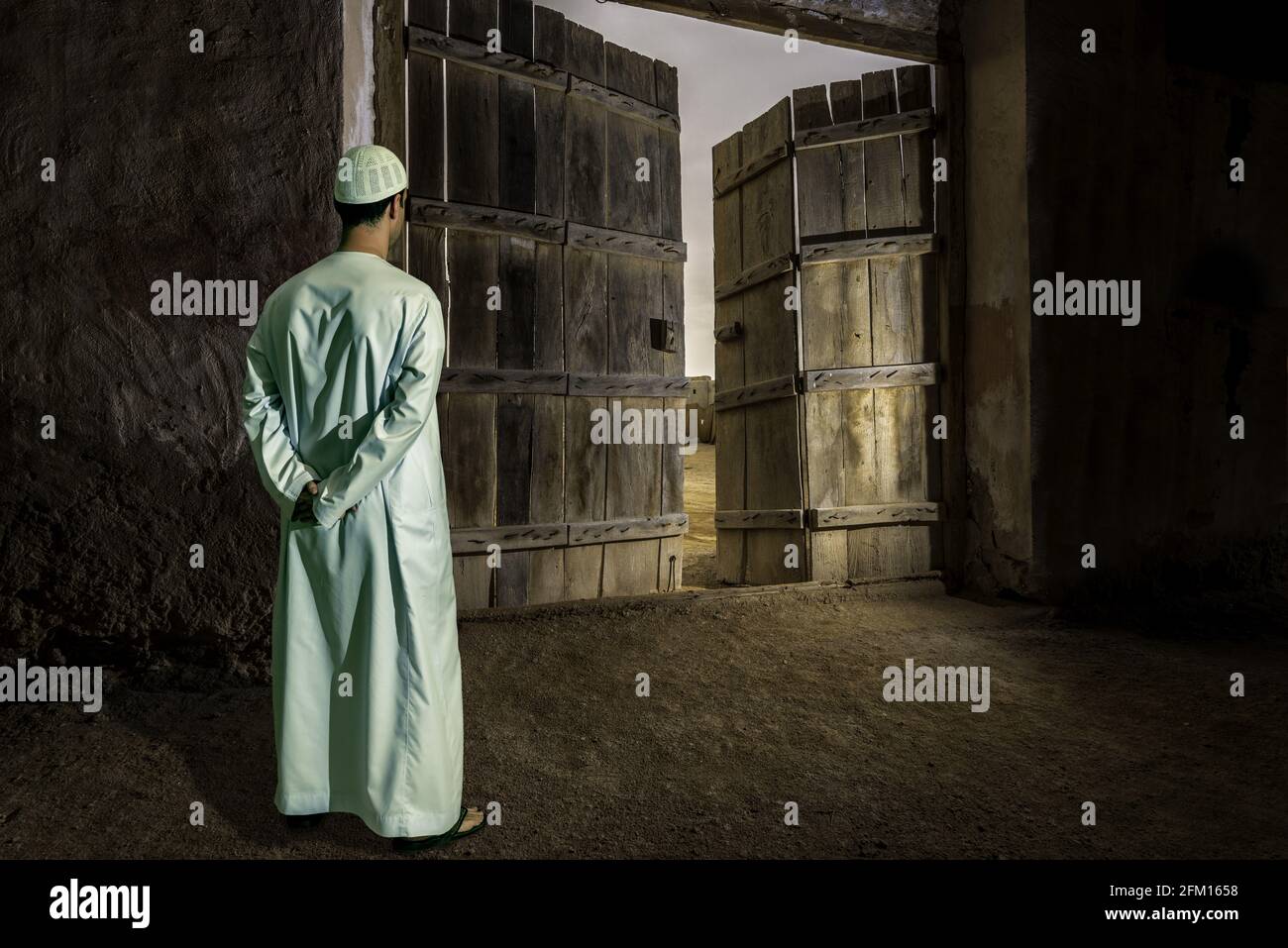 Muslim male wearing a thawb standing in a warehouse looking at the open ...