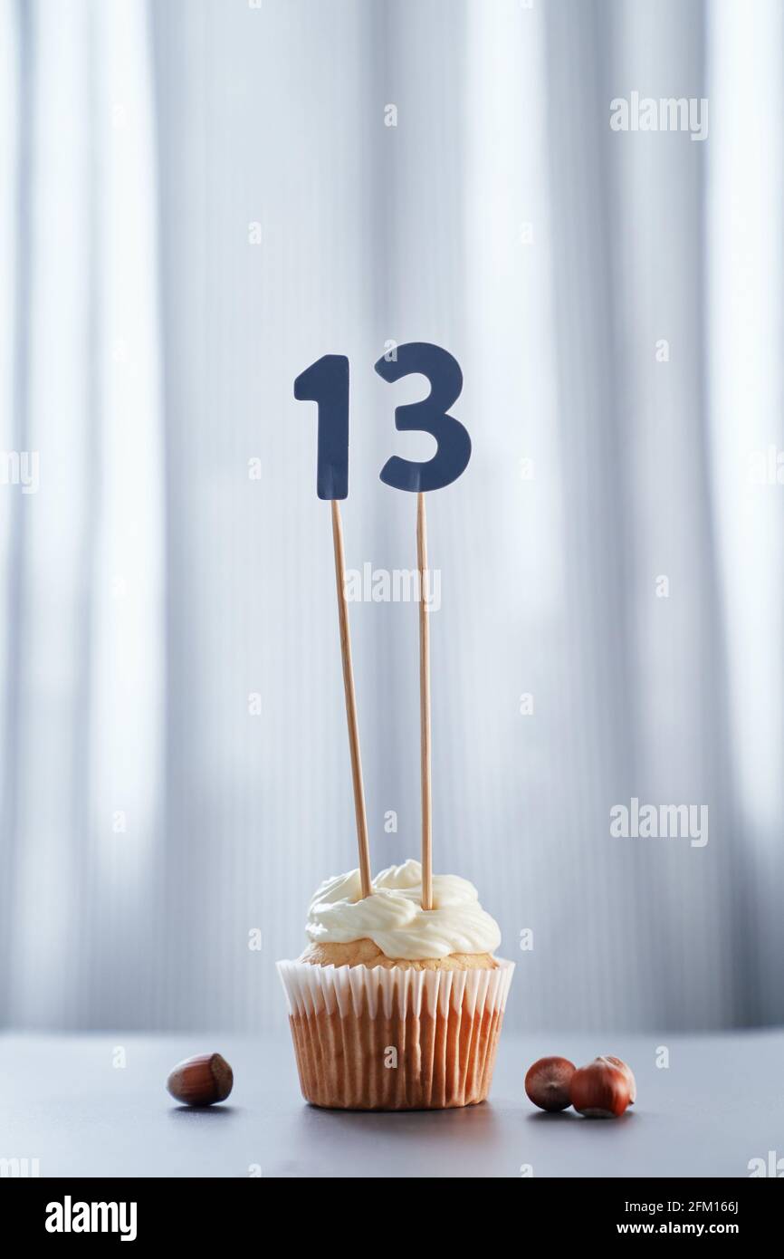 Birthday cupcake or muffin with number 13 thirteen and hazelnuts on ...