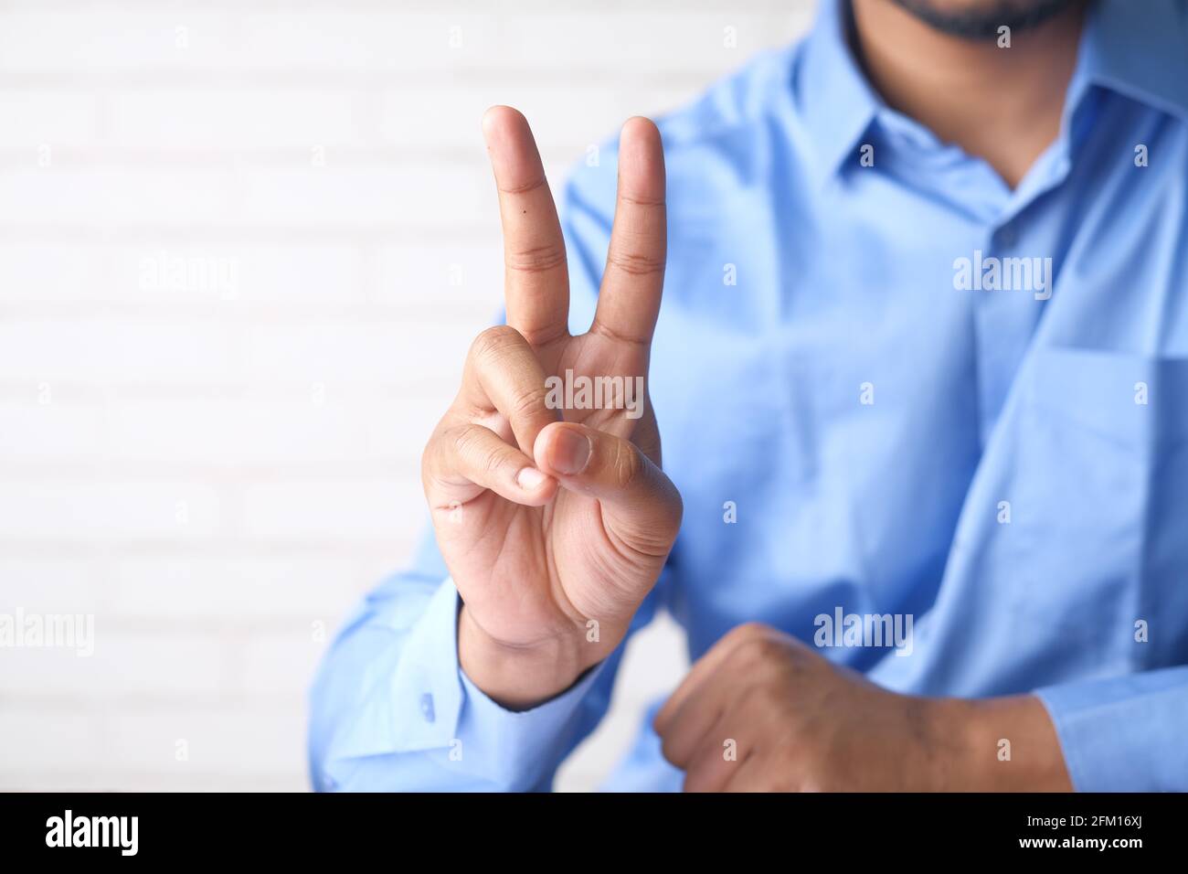 man hand showing victory gesture on white background Stock Photo - Alamy