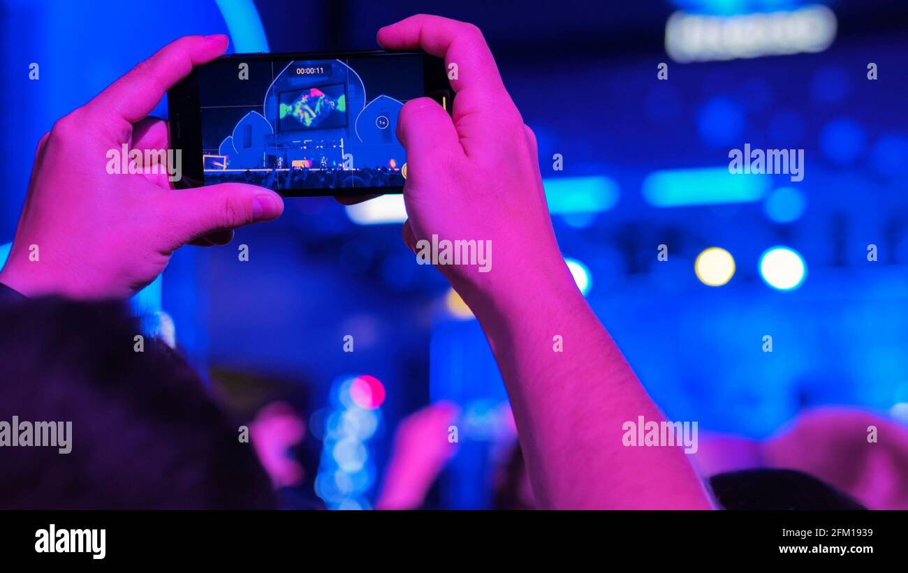 Hands silhouette recording video of live music concert with smartphone ...