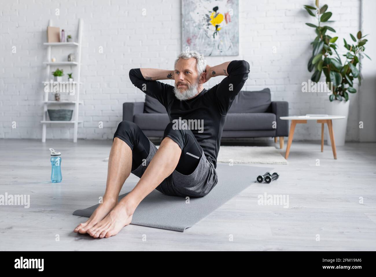 barefoot man working out on fitness mat in modern living room Stock ...