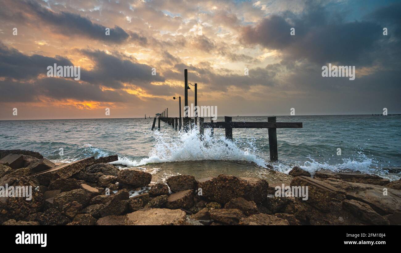 Scenic view of the wavy ocean hitting the rocky beach gleaming under ...