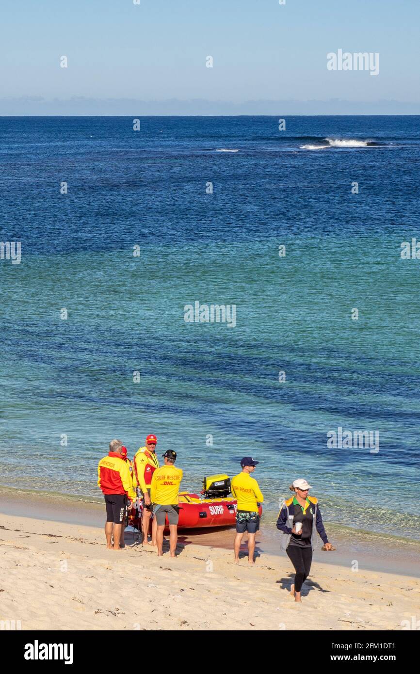 Surf lifesavers standing by an inflatable rescue boat on the shore at ...